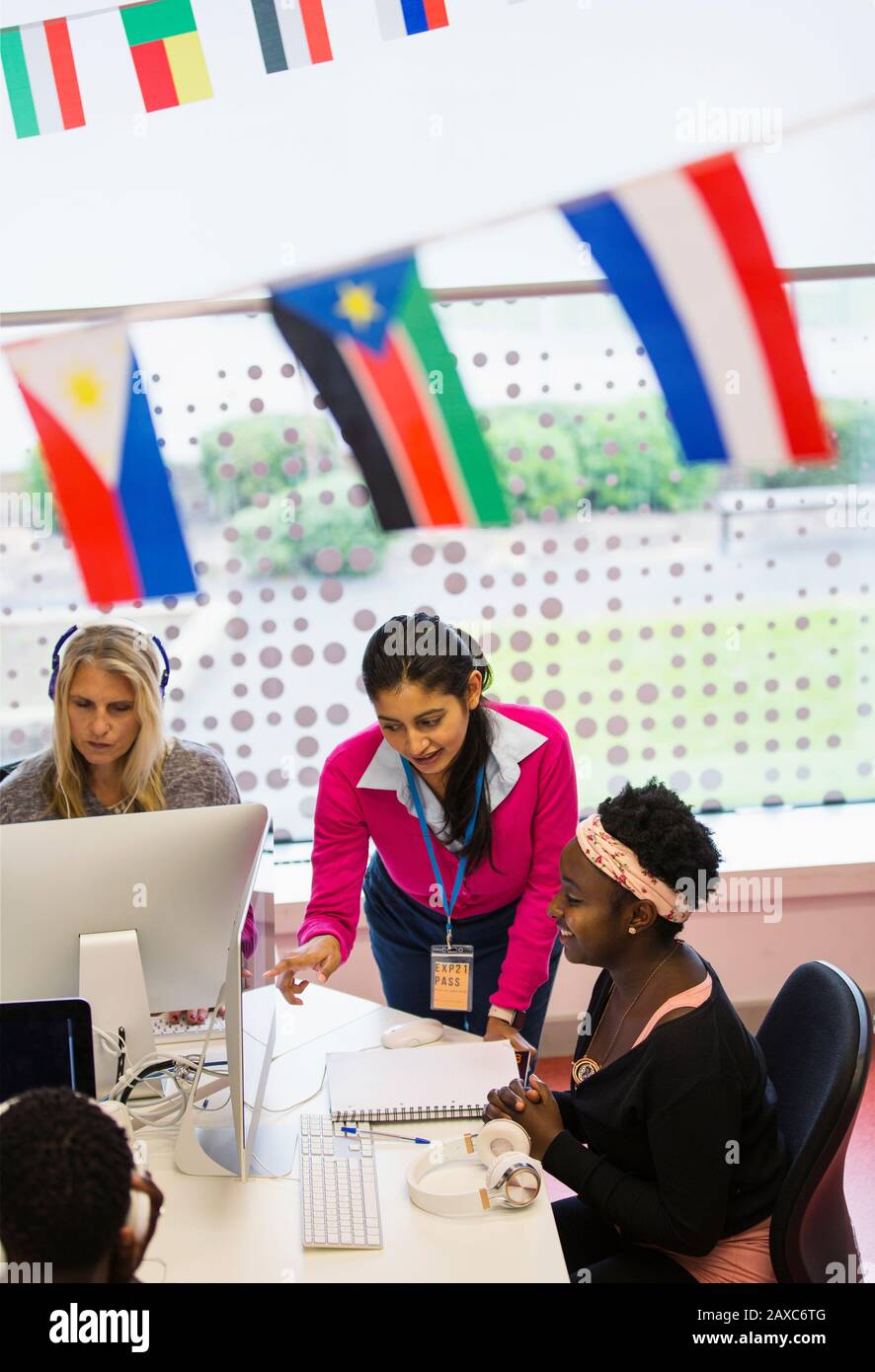 Female community college instructor helping student at computer in ...