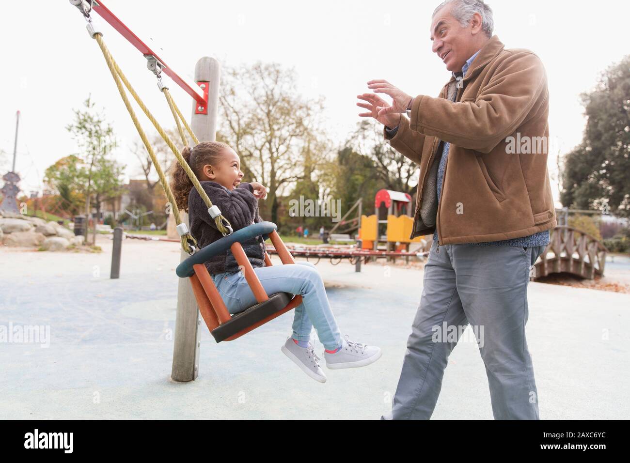 Grandfather pushing granddaughter on playground swing Stock Photo - Alamy