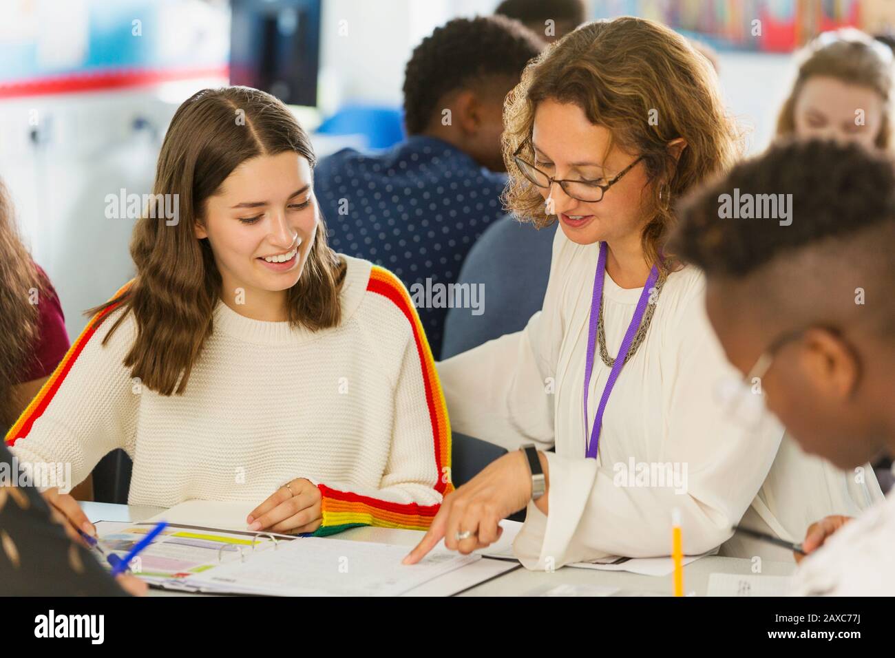 Female high school teacher helping girl student with homework in ...