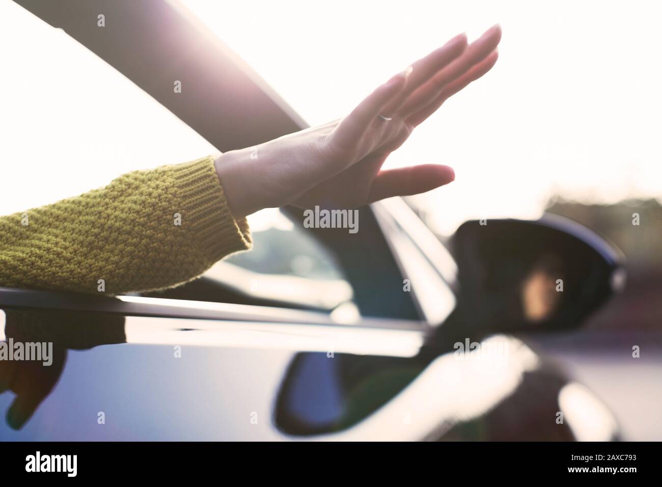Carefree woman reaching hand out car window Stock Photo - Alamy