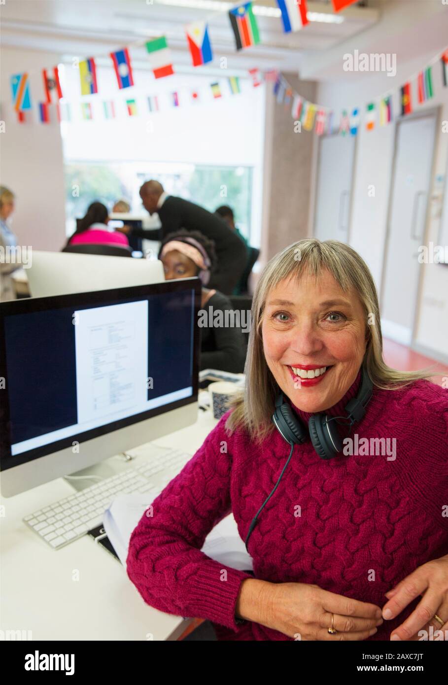 Portrait confident mature female student at computer in computer lab ...