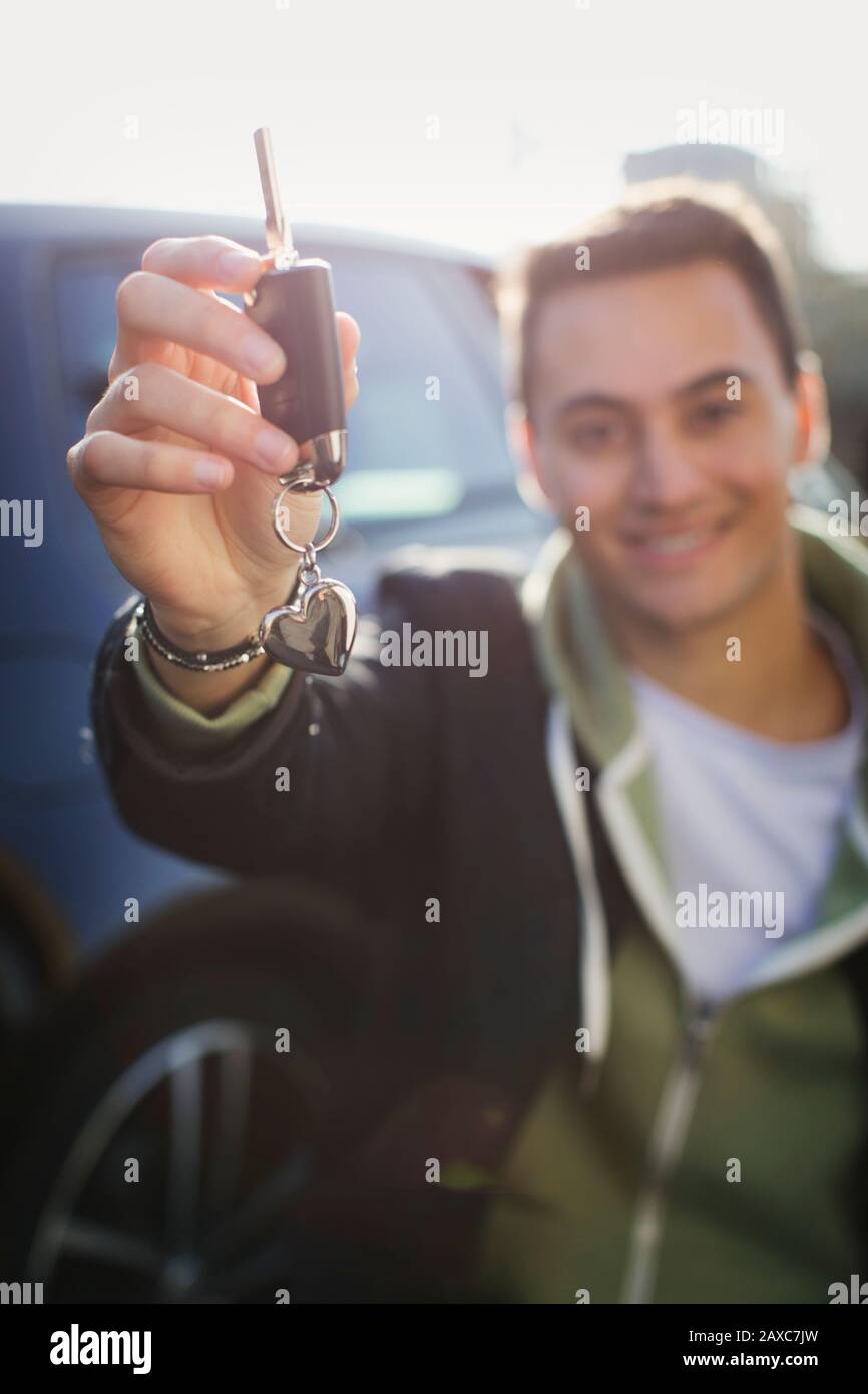 Portrait happy young man holding new car keys with heart-shape key ...