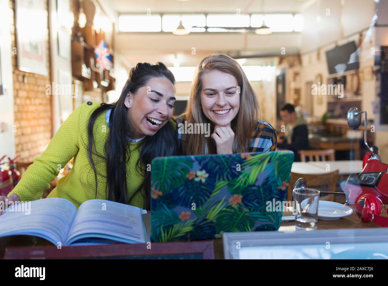 Happy, laughing young female college students using laptop in cafe ...