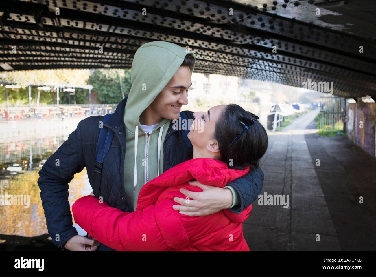 Happy, affectionate young couple hugging under urban bridge Stock Photo ...