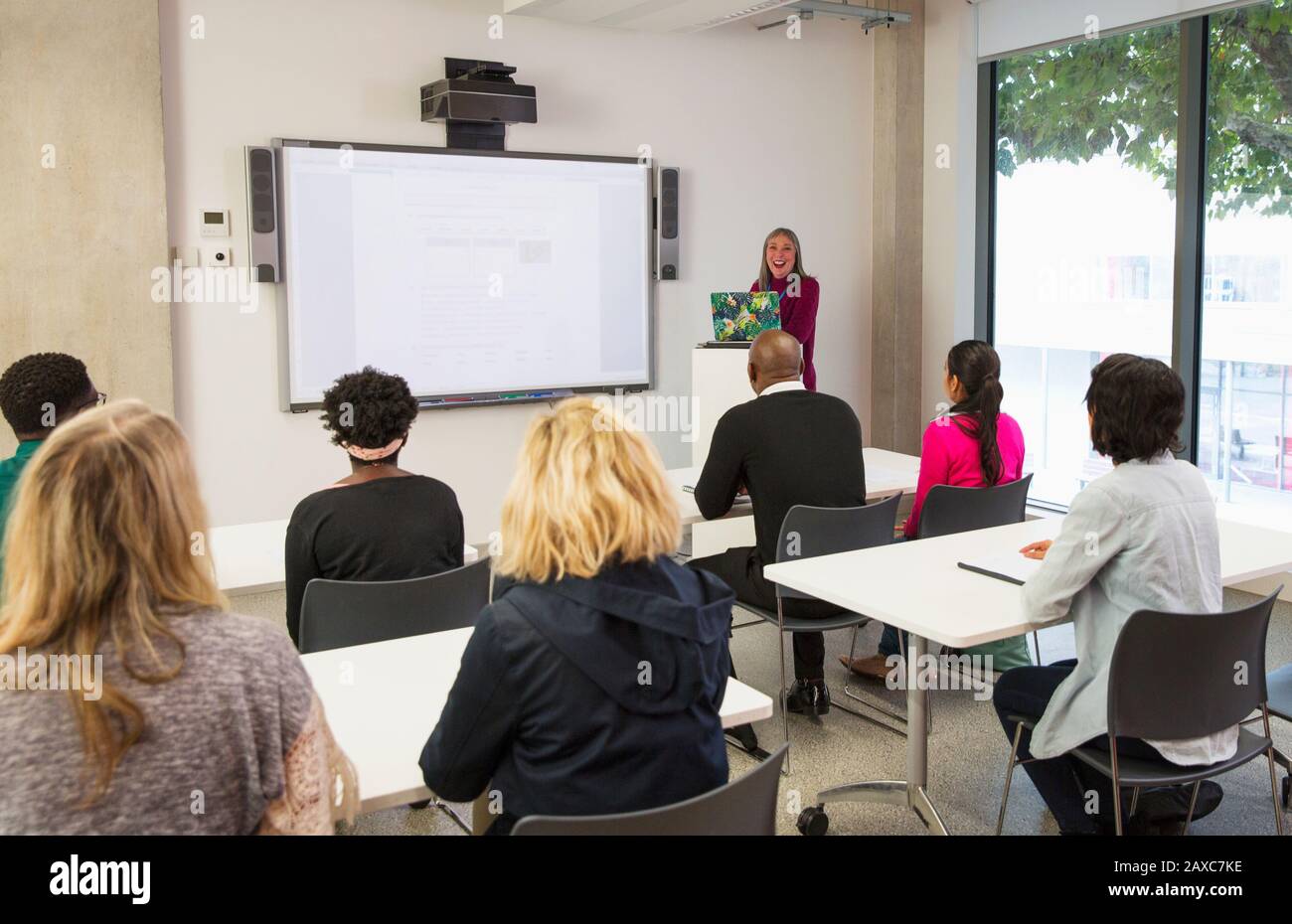 Female community college instructor leading lesson at projection screen ...