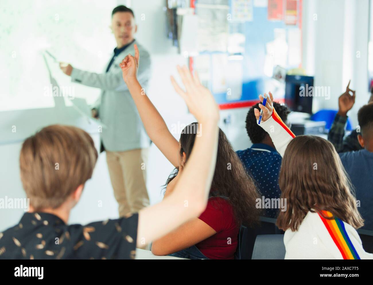 High school students with hands raised during lesson in classroom Stock ...