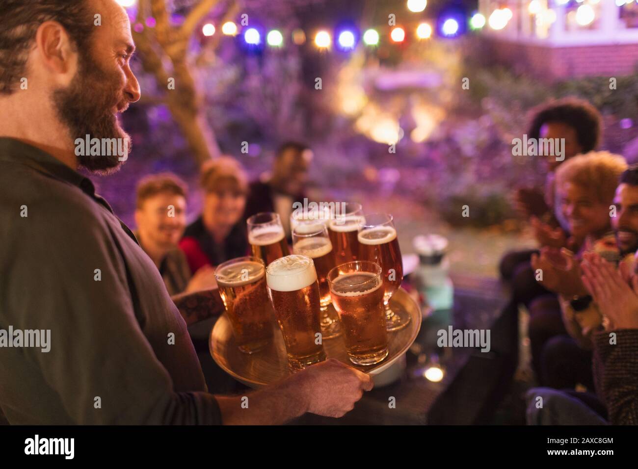 Man serving tray of beers to friends at garden party Stock Photo - Alamy
