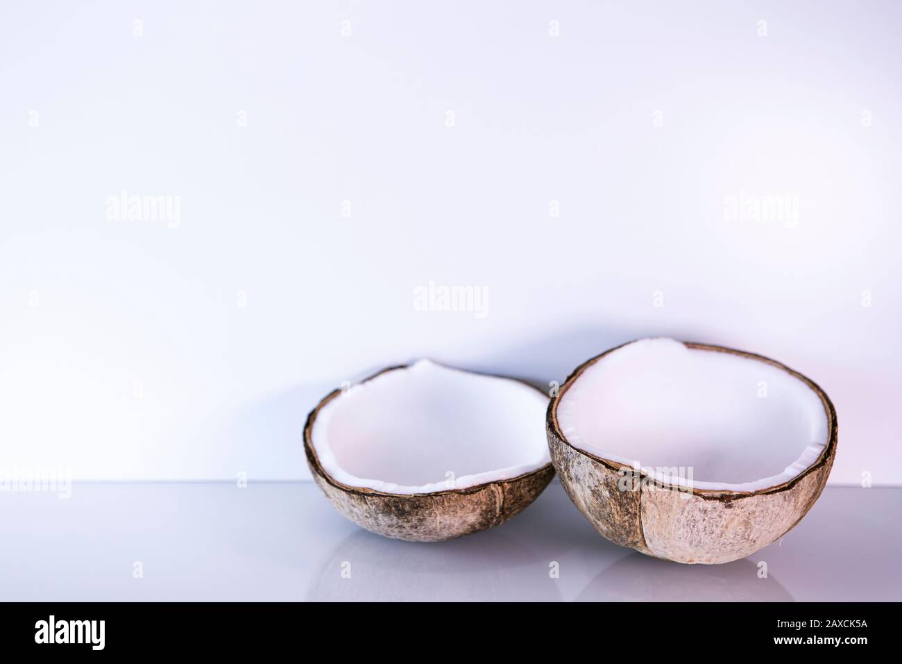 Two halves of coconut are lying on smooth bright background. Tropical ...