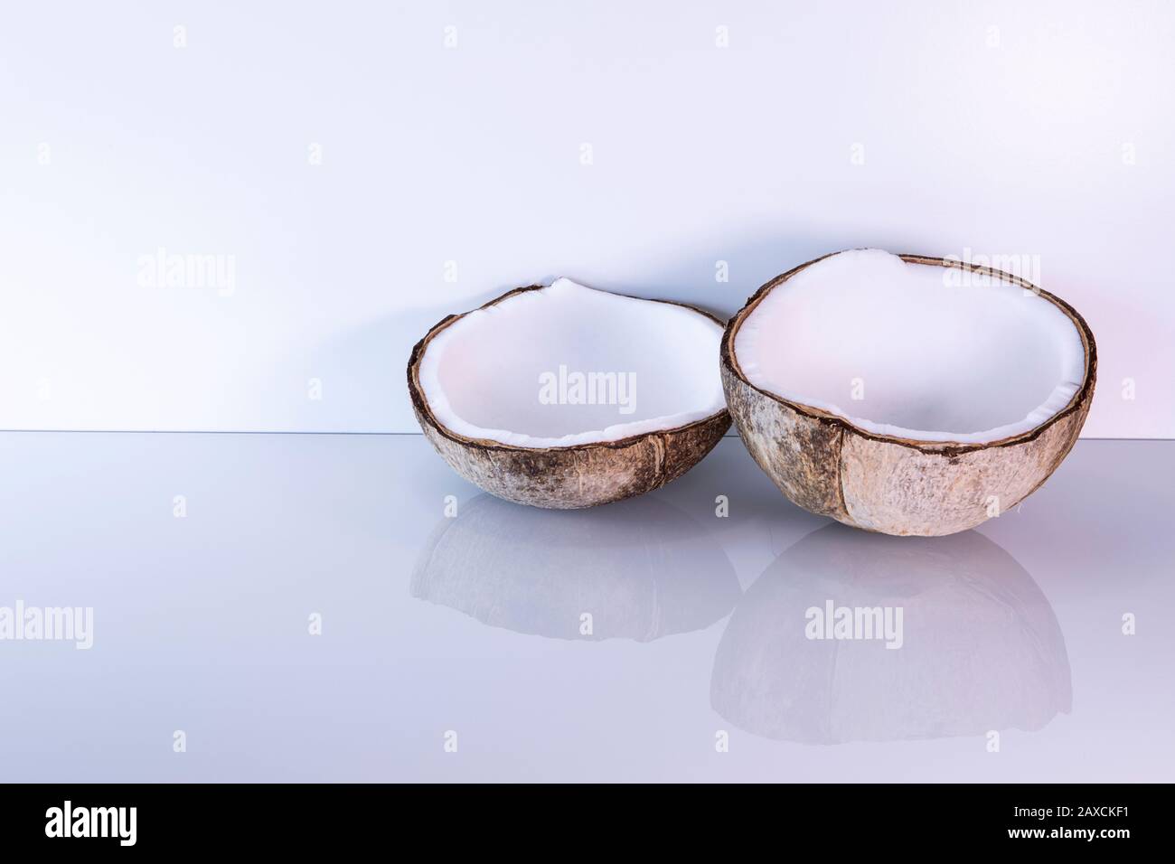 Two halves of coconut are lying on smooth bright background. Tropical ...