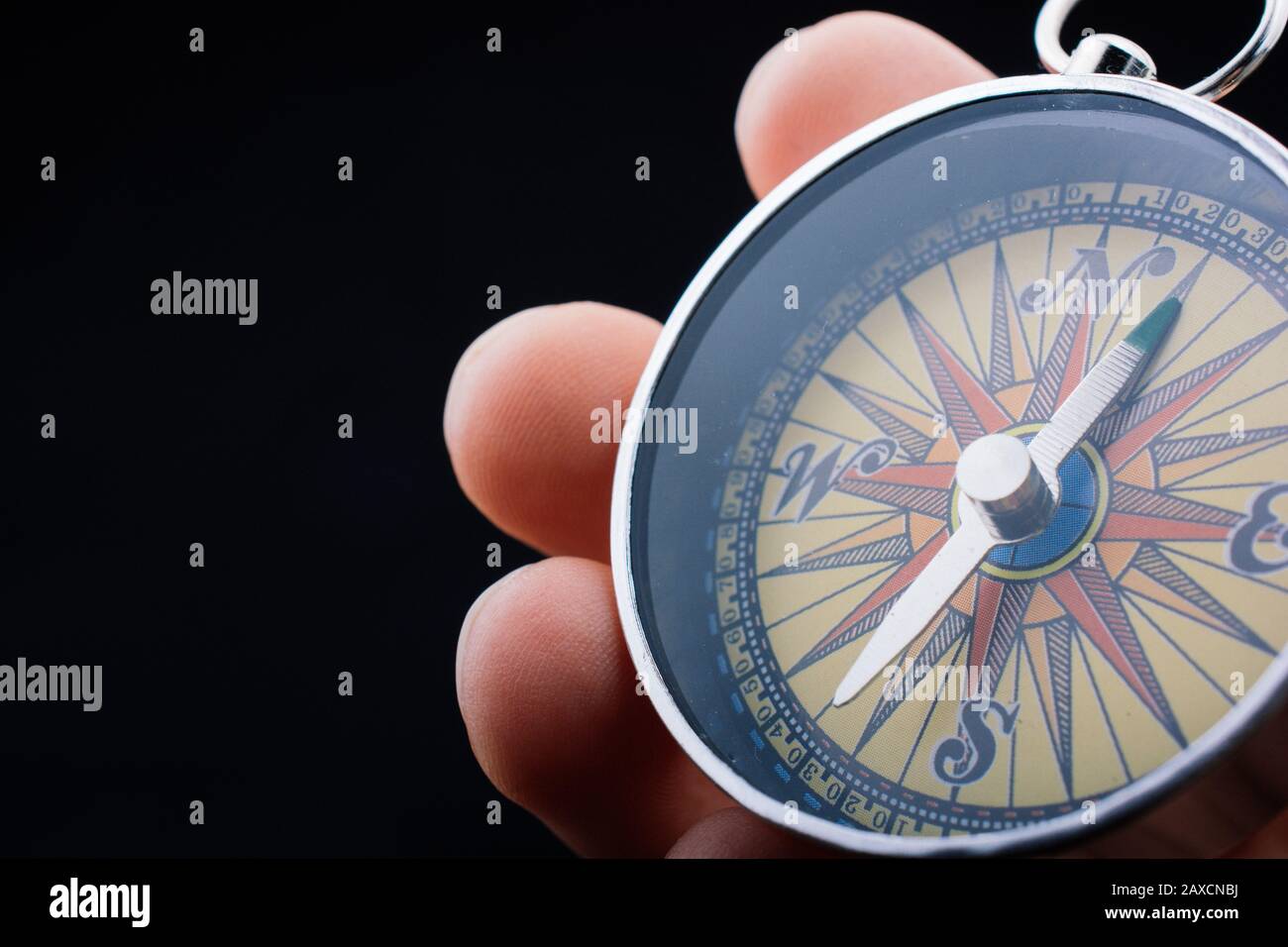 Hand is holding a magnetic compass on black background Stock Photo - Alamy