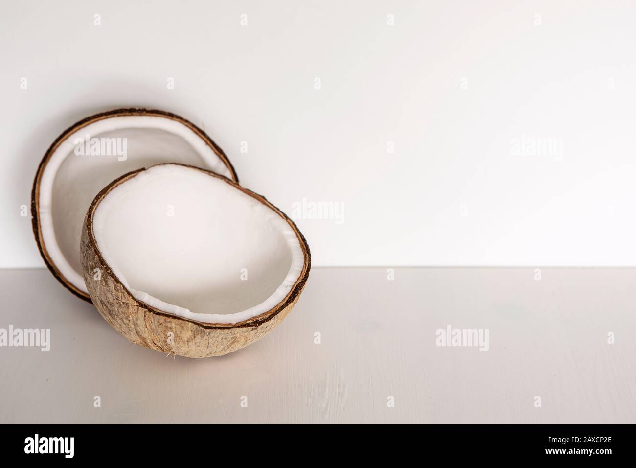 Broken coconut on white warm background with copy space. Open coco ...