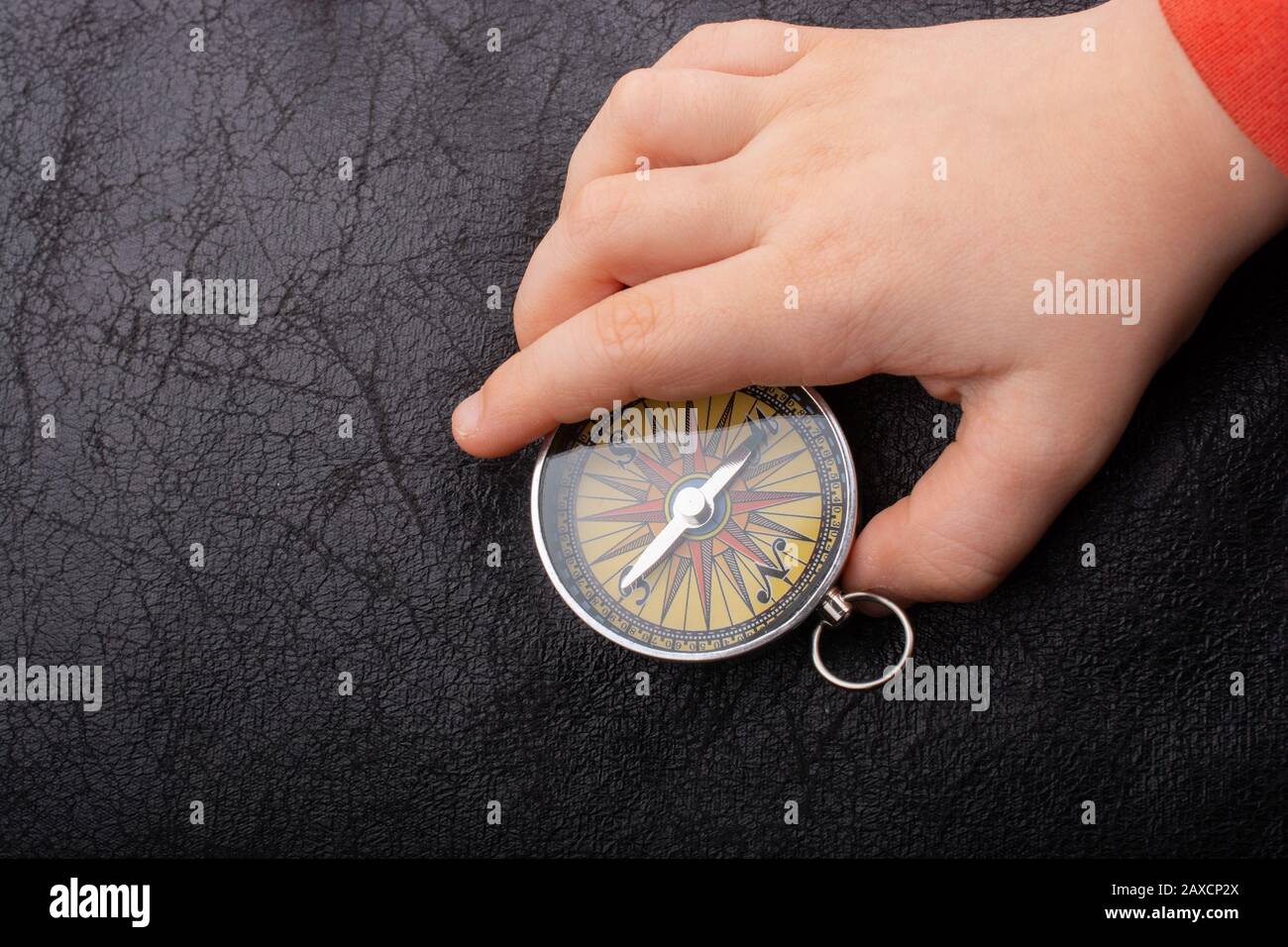 Hand is holding a magnetic compass on black background Stock Photo - Alamy