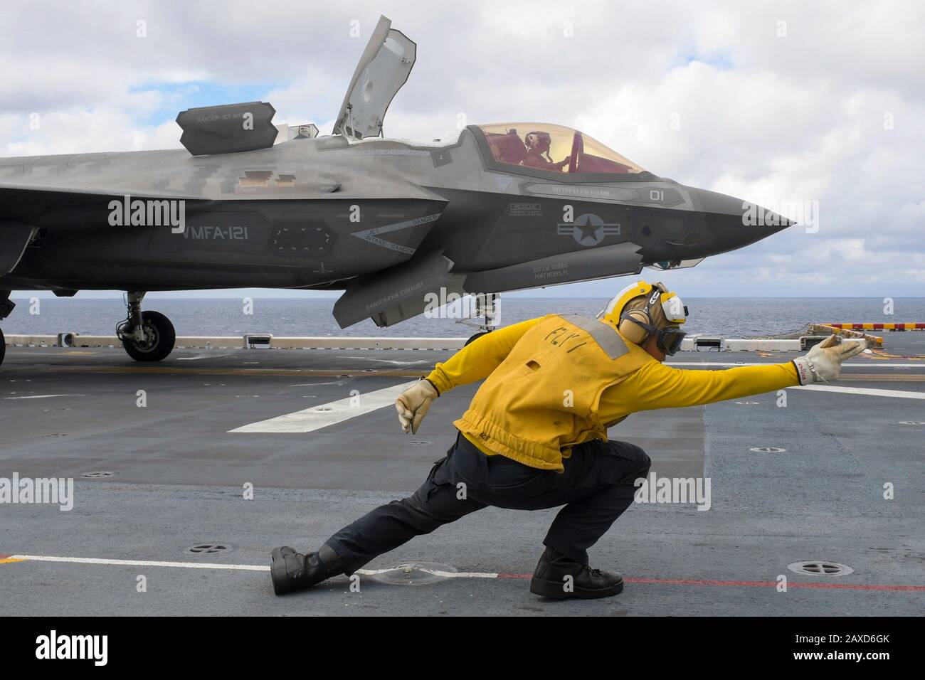 A U.S. Navy flight handler signals a Marine Corps F-35B Lightning II ...