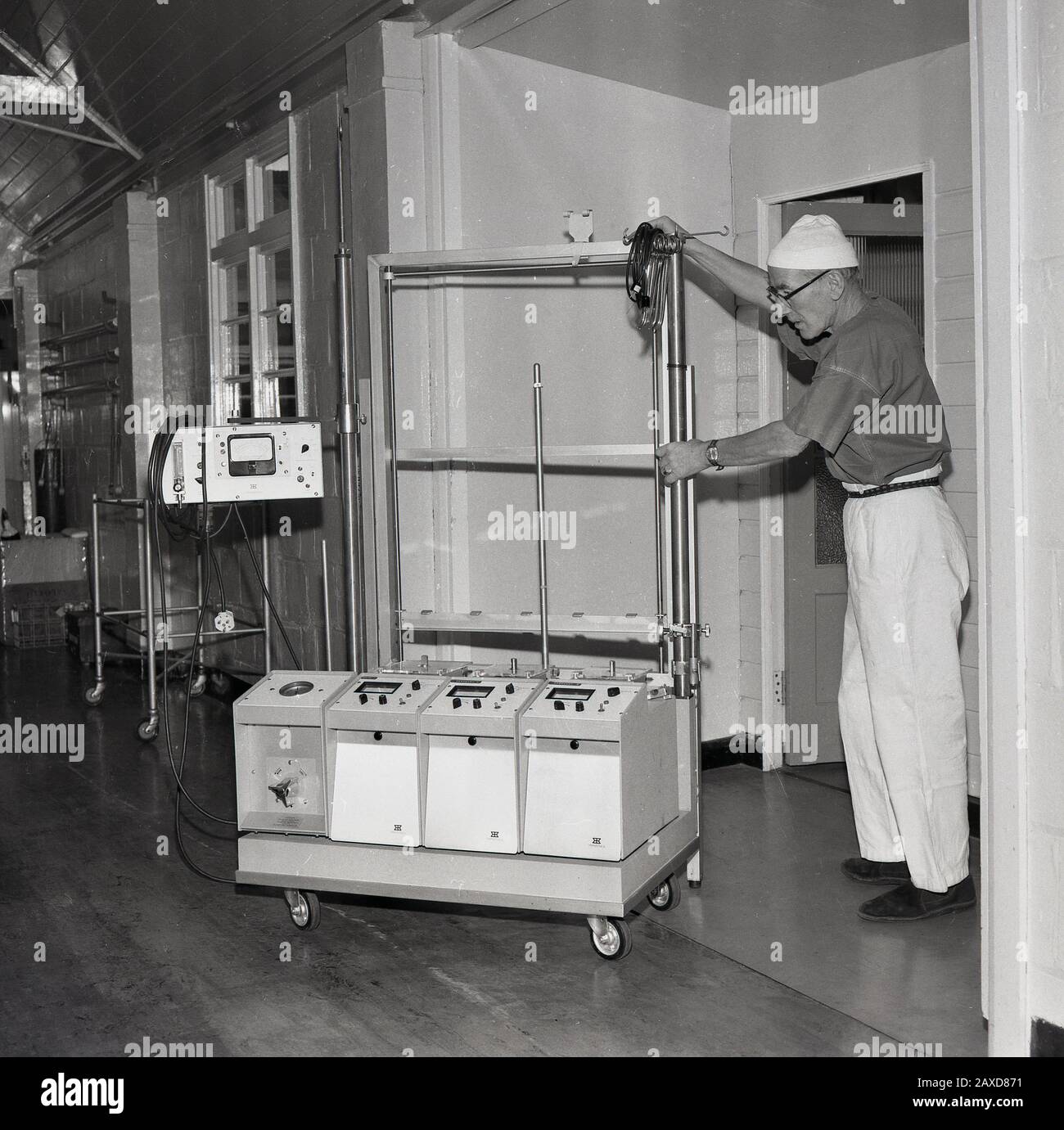 1960s, historical, an elderly hospital porter moving medical monitors ...