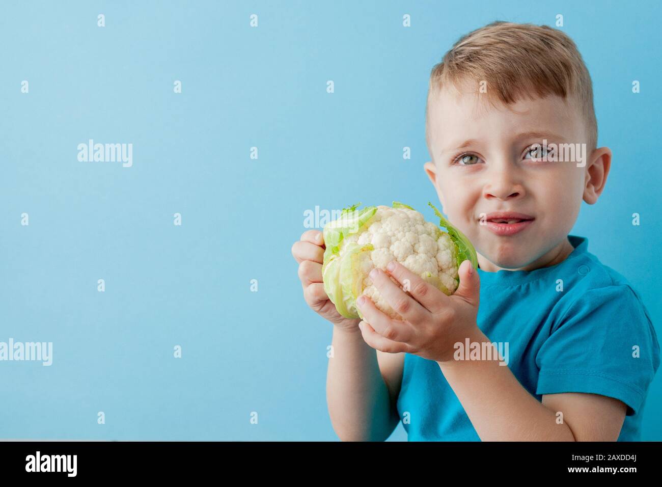 Little Boy Holding Broccoli in his hands on blue background, diet and ...