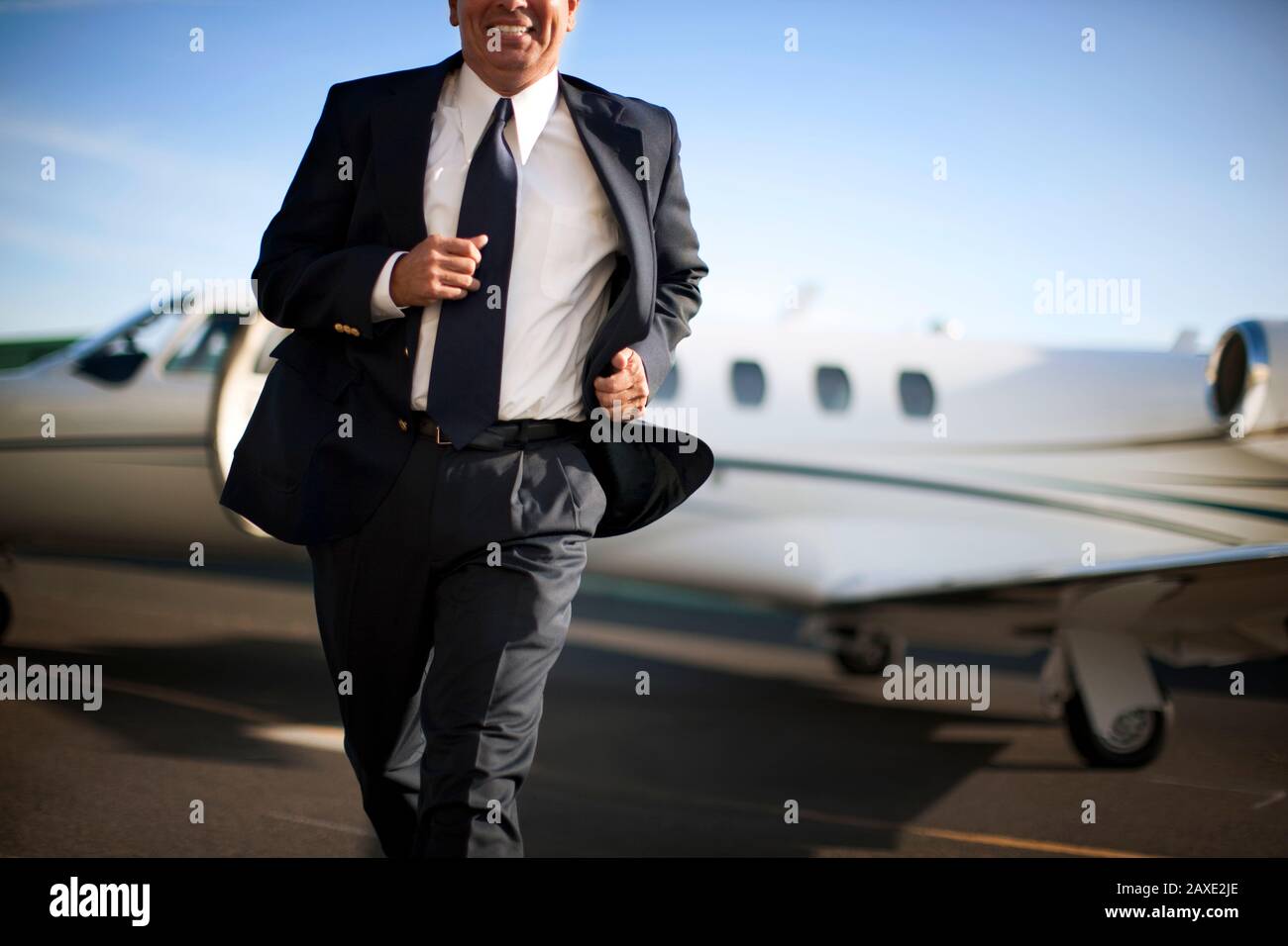 A businessman running from a plane at the airport Stock Photo - Alamy