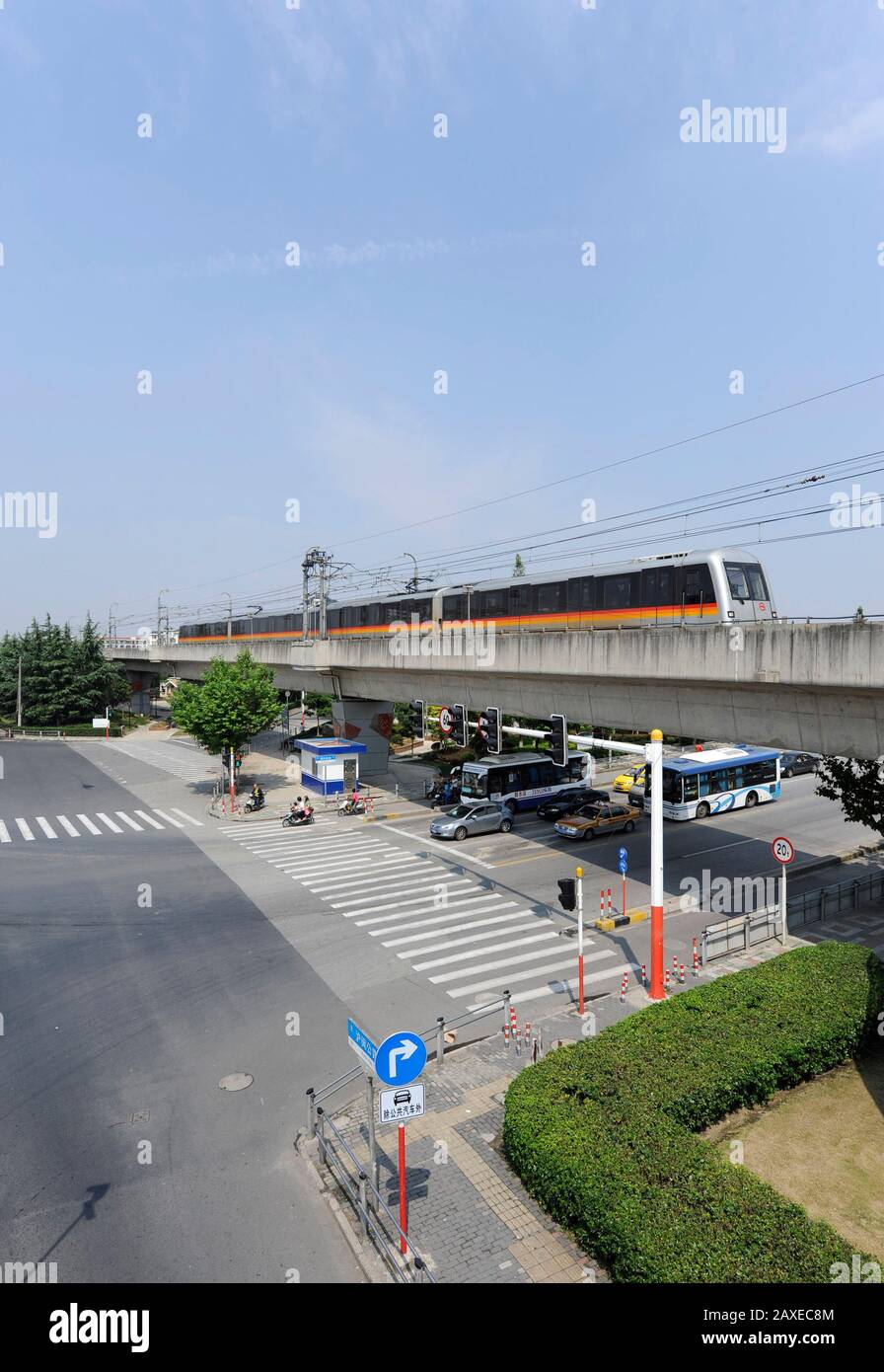 Shanghai metro line 5 train approaches a station over a roadbridge ...