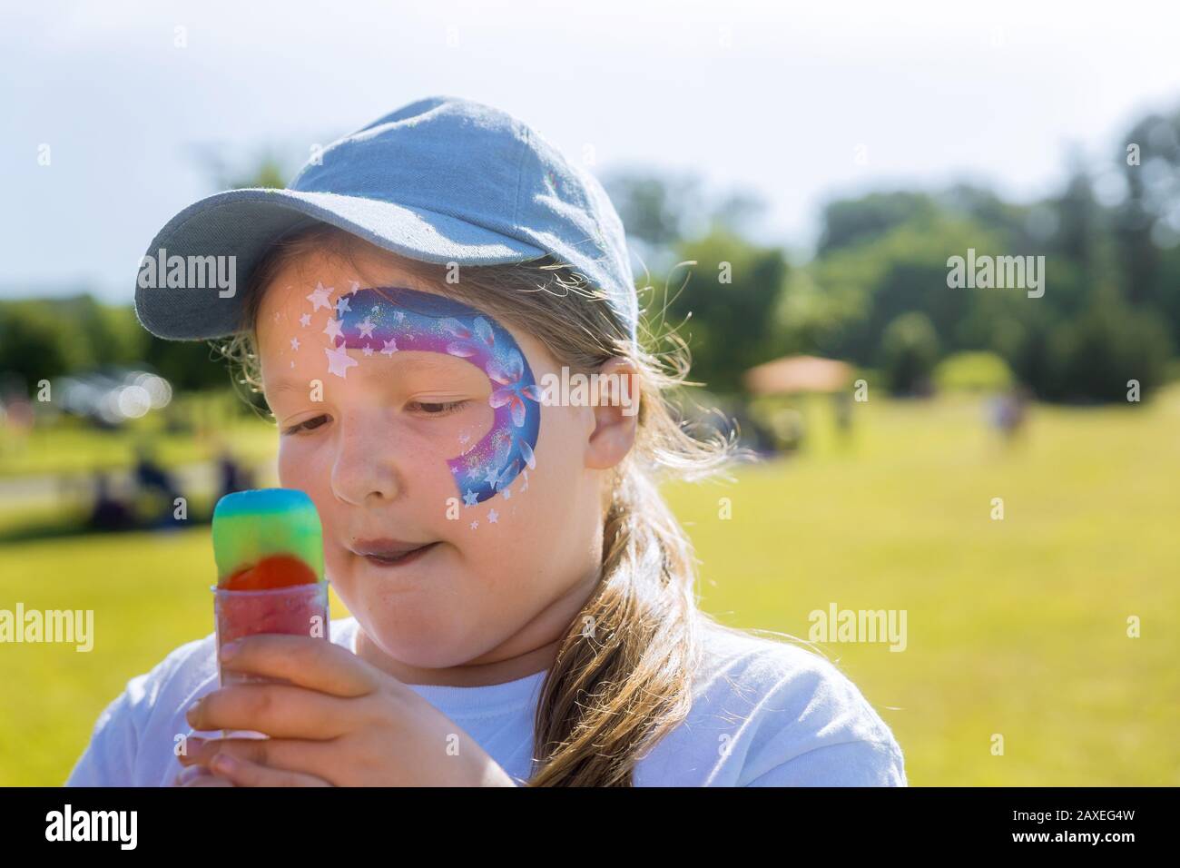 Teenager with face paint eating rainbowl color ice cream Stock Photo ...