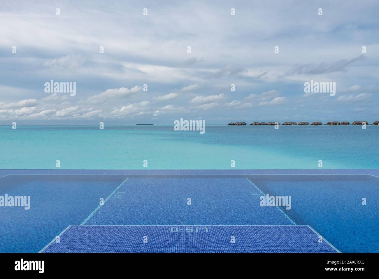 A brilliant blue infinity swimming pool beside the turquoise sea on an ...
