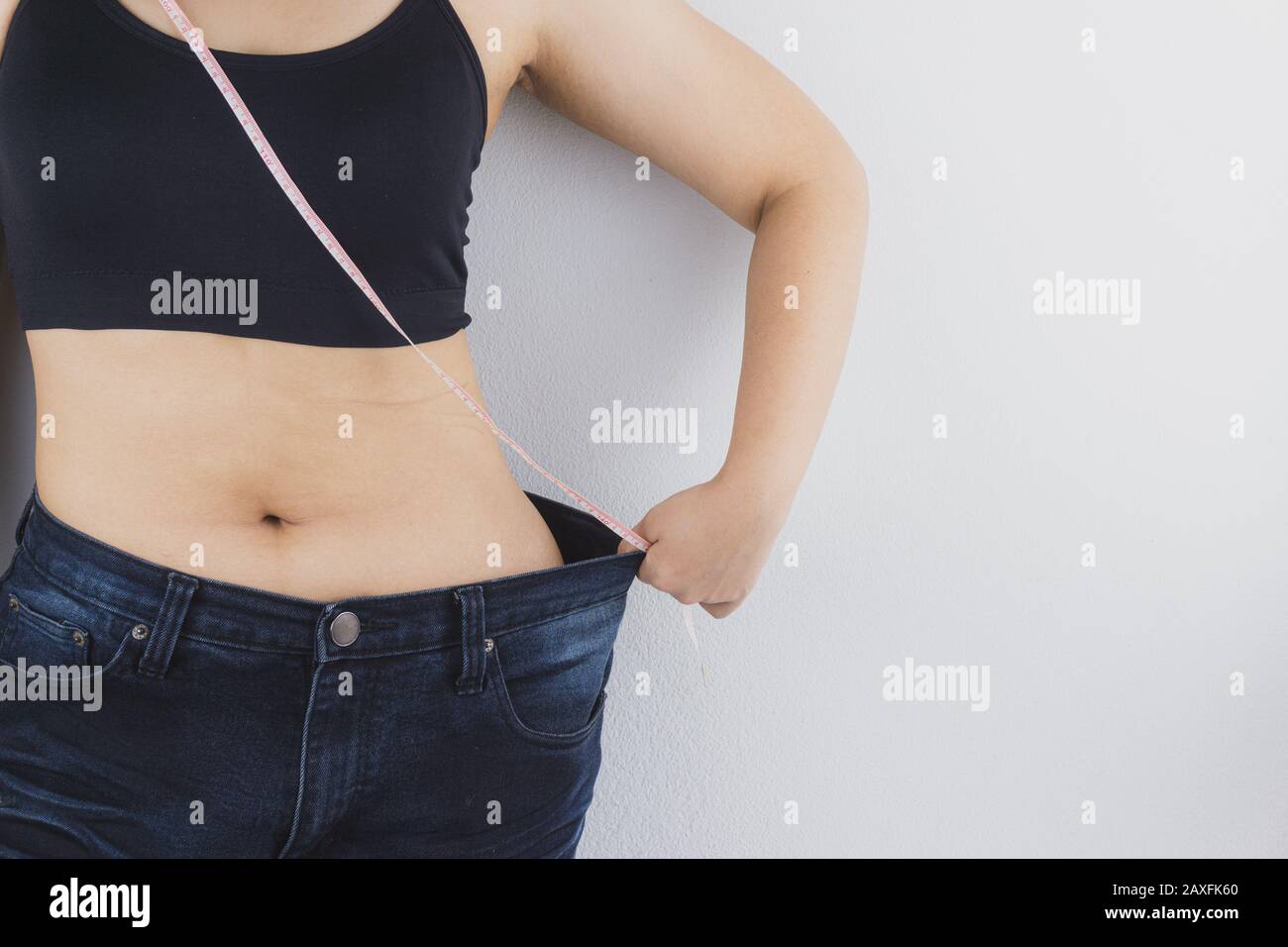 Close up shot of woman with slim body measuring her waistline and torso ...