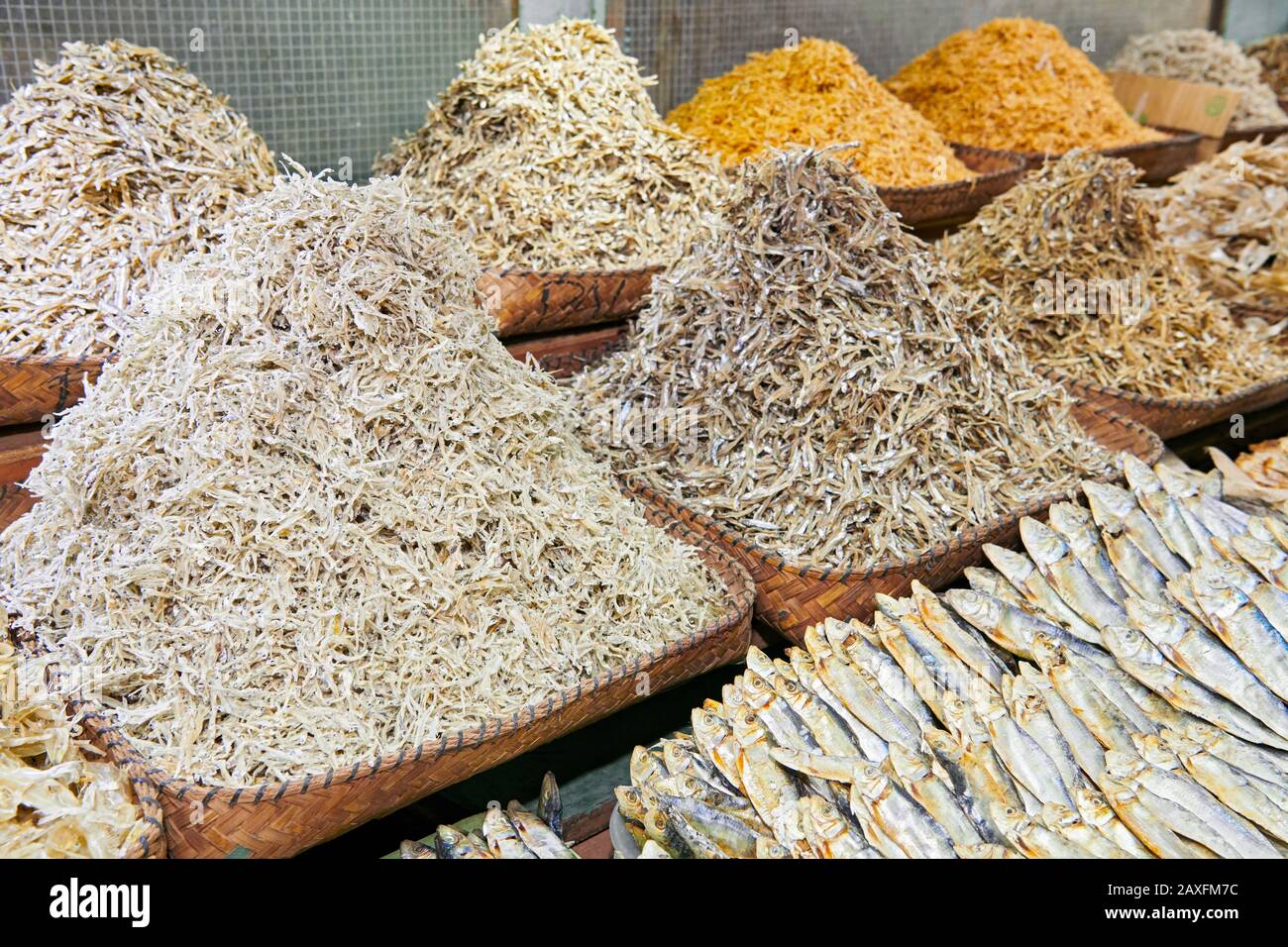 Close-up of heaps of dried and salted small fishes in bamboo baskets at ...