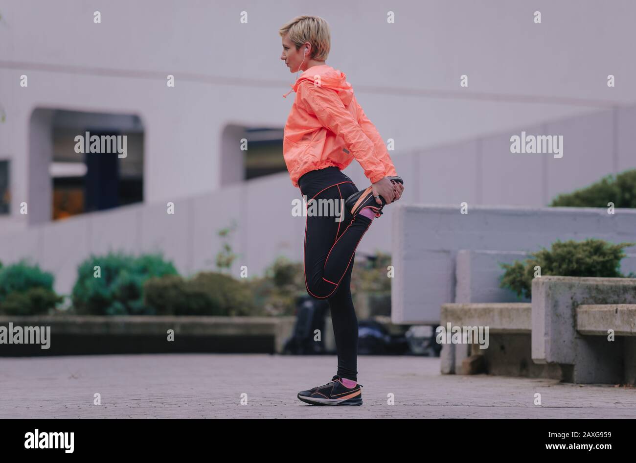 Athletic fit female runner squatting in an urban environment Stock ...