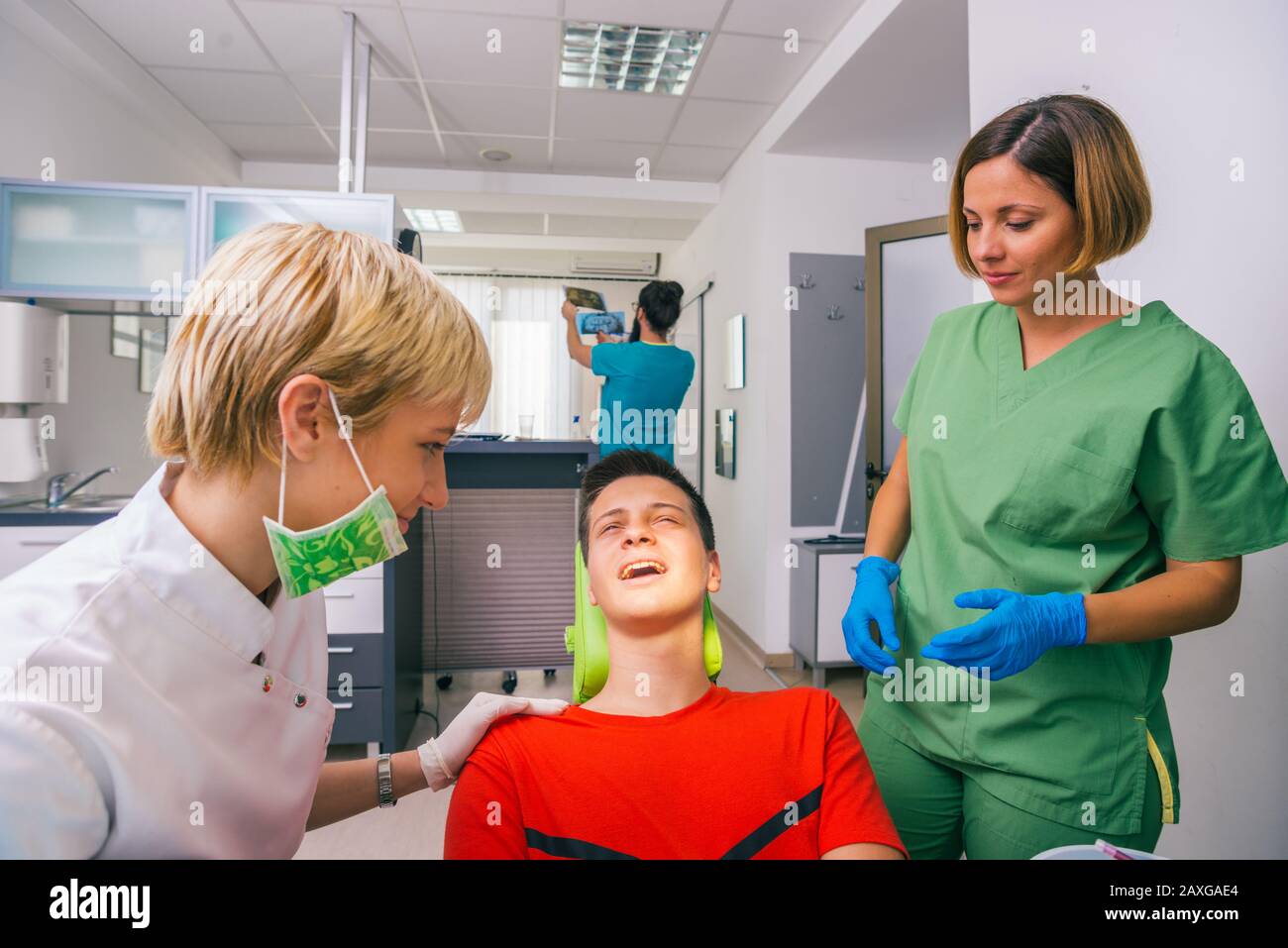 Female dentist with the help of her dentist technician examines the ...