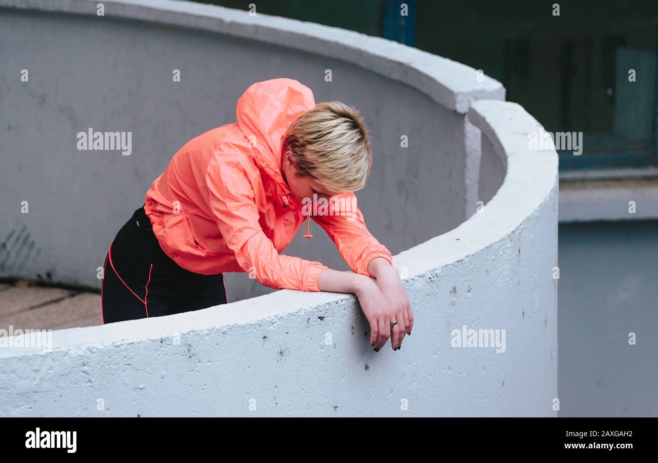 Young female runner taking a break during an urban workout routine ...
