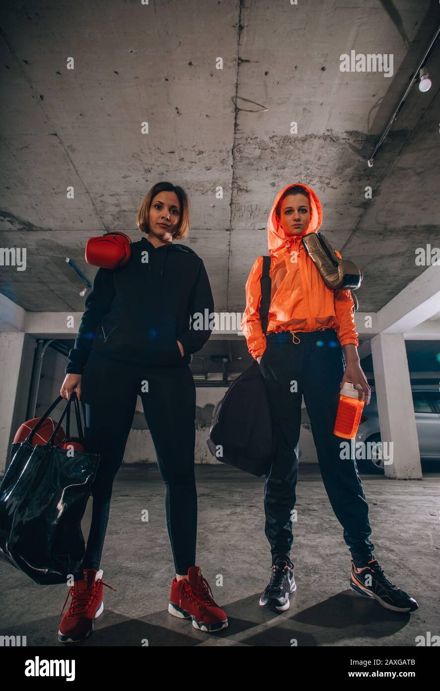Two female boxer friends standing in a garage with boxing equipment ...