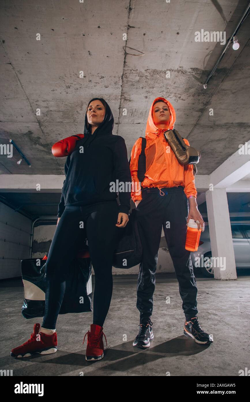 Two female boxer friends standing in a garage with boxing equipment ...