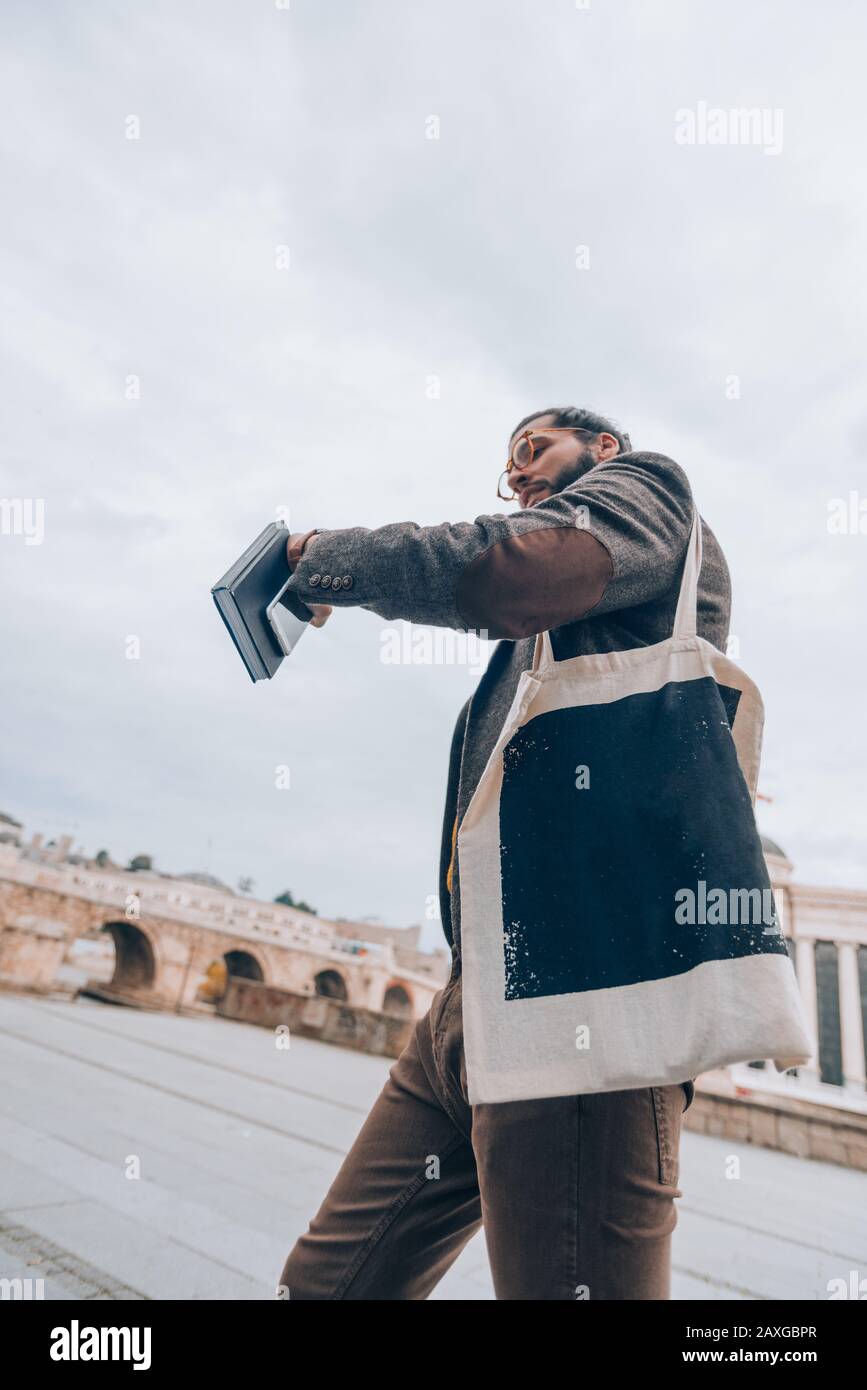 Hipster trendy guy wearing classy outfit holding bag and book while ...