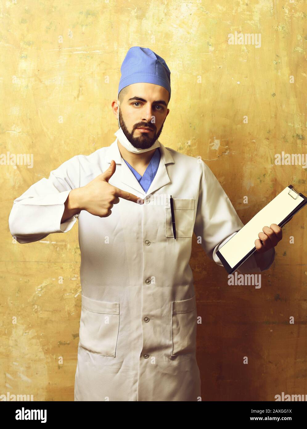 Surgeon in white coat and blue cap with dark beard and assured face ...
