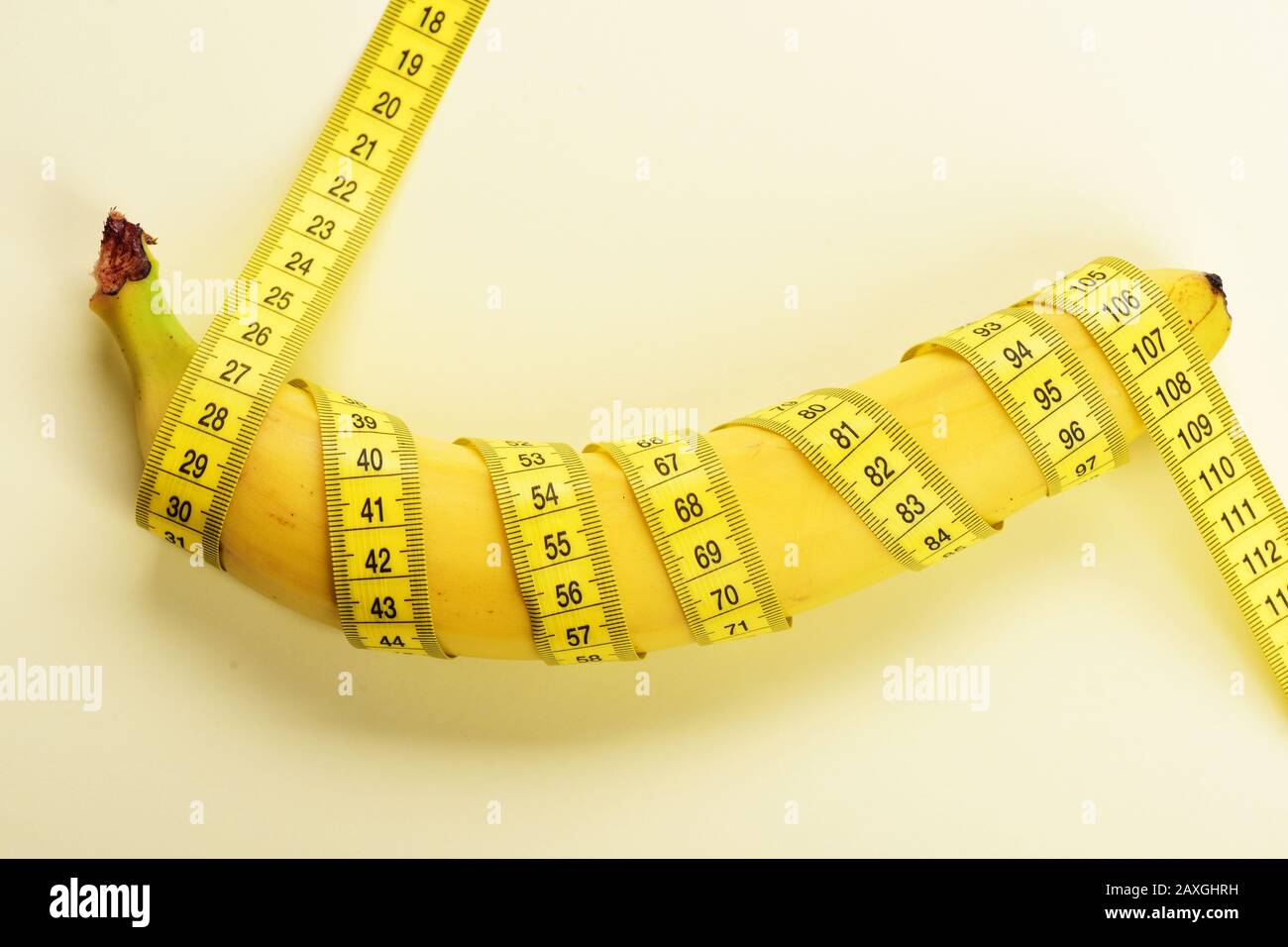 Centimeter ruler spinned around fresh fruit. Banana with yellow tape ...