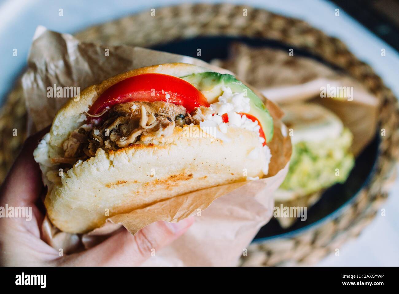 Venezuelan arepas on a table, a hand holding one arepa ready to eat ...