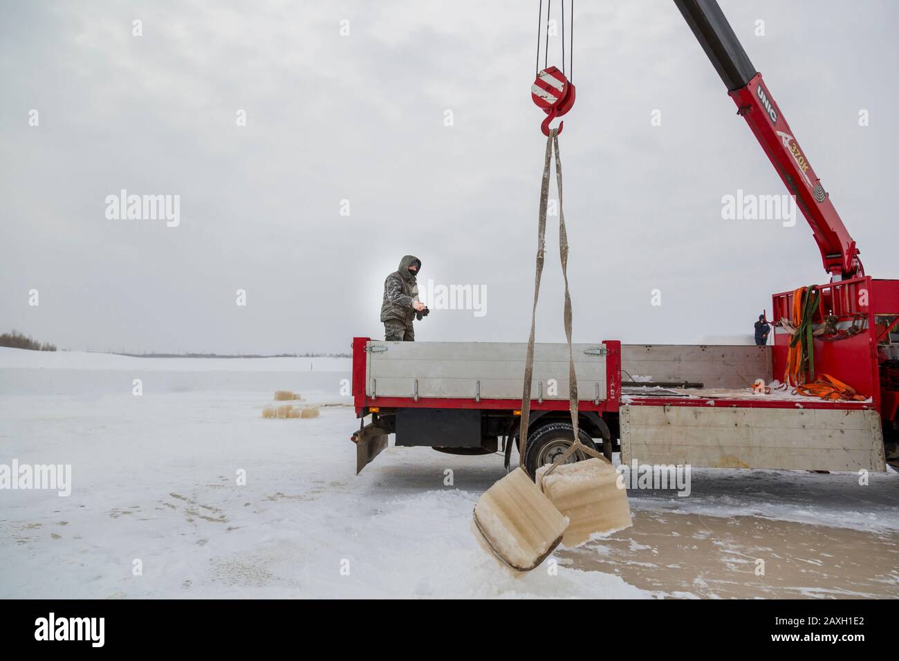 Slinger works with a truck crane on ice Stock Photo - Alamy