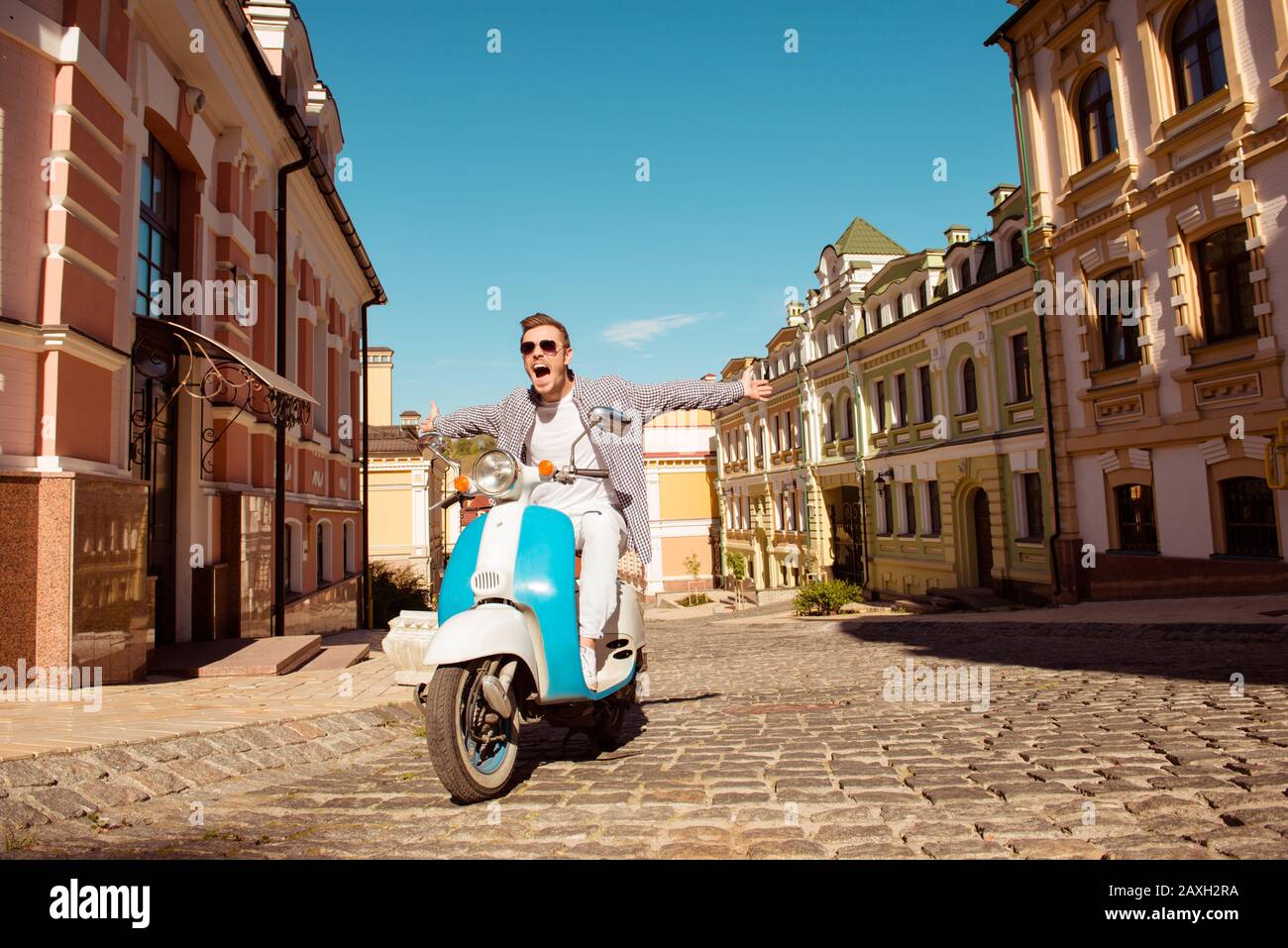 Portrait of free happy man riding scooter with open hands and screaming ...