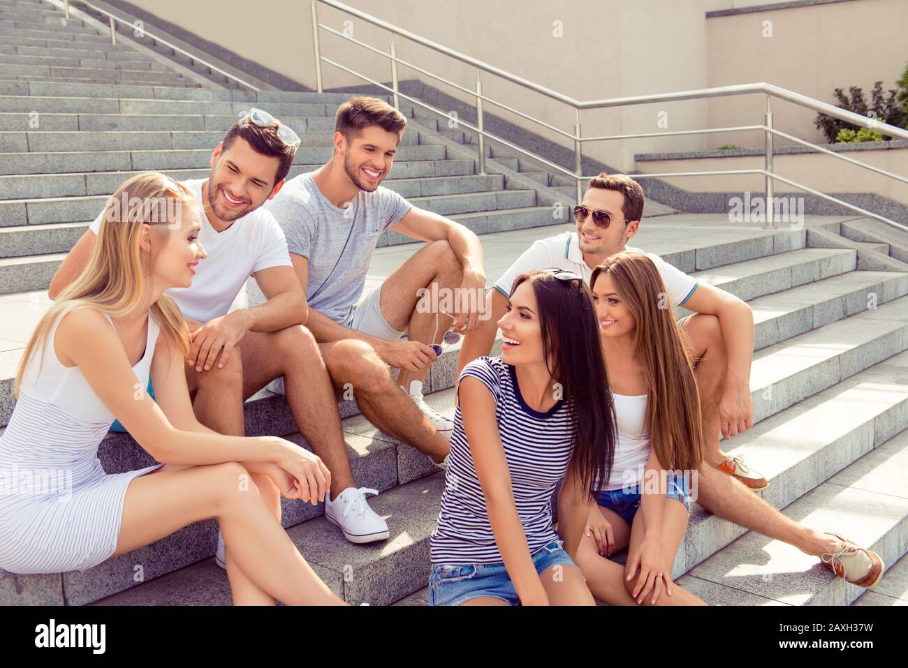 relaxing joyful friendly six friends talking while sitting on stairs on ...