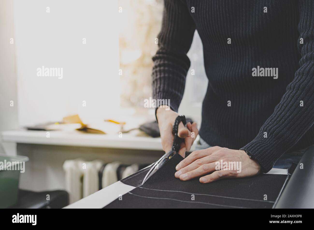 Hands of a male worker cut fabric with large scissors. Hand labor ...