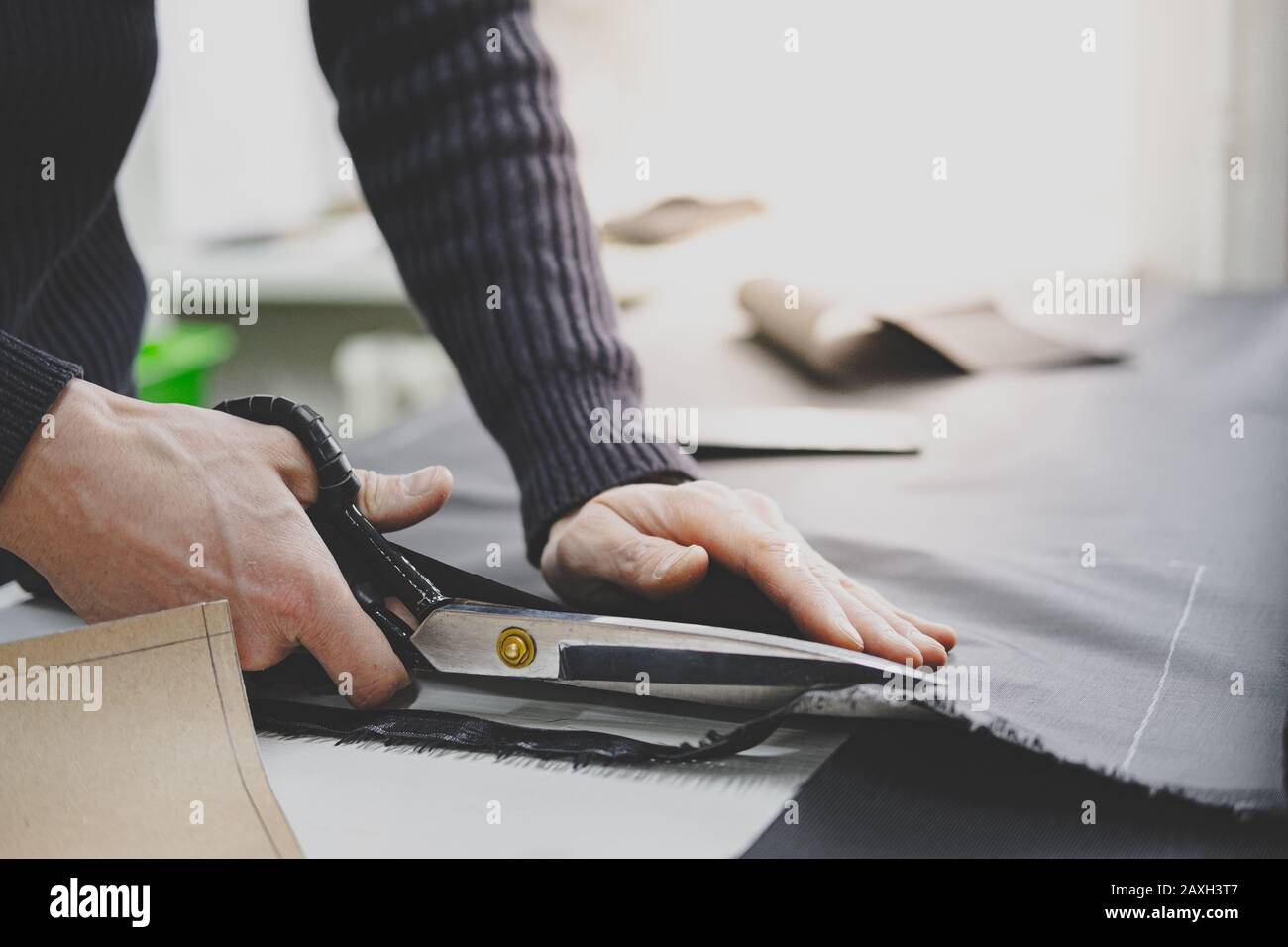 Hands of a male worker cut fabric with large scissors. Hand labor ...
