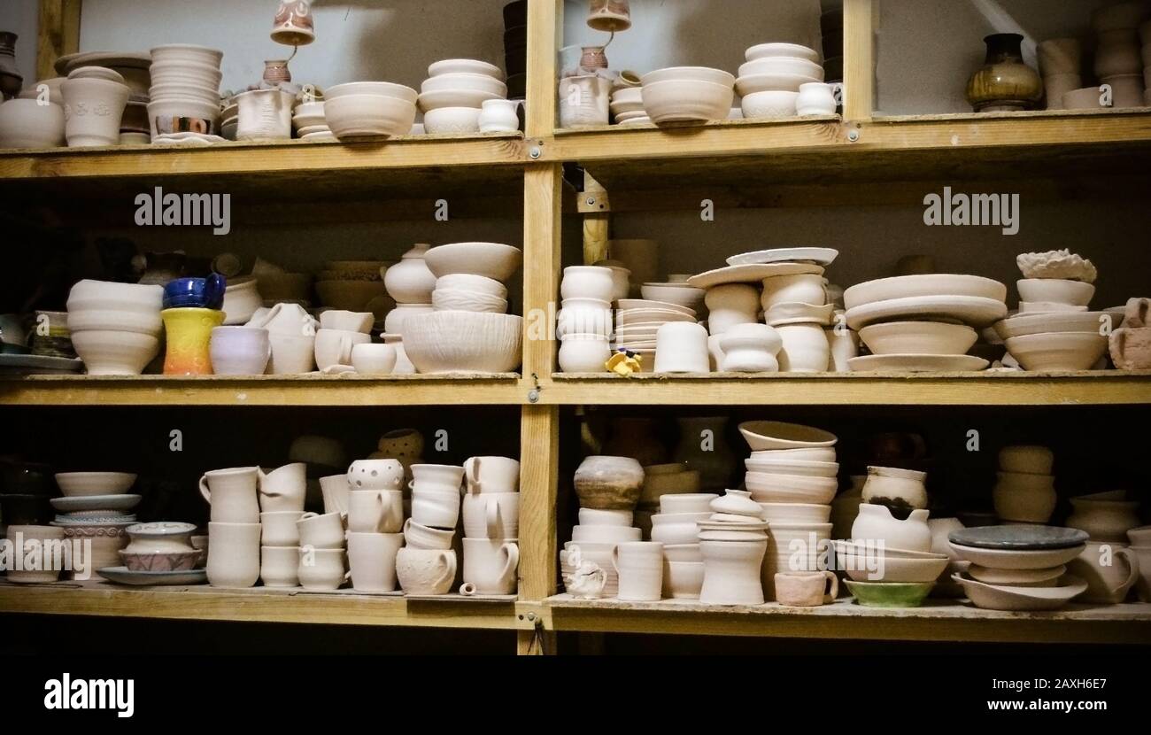 many different pottery standing on the shelves in a pottery workshop ...