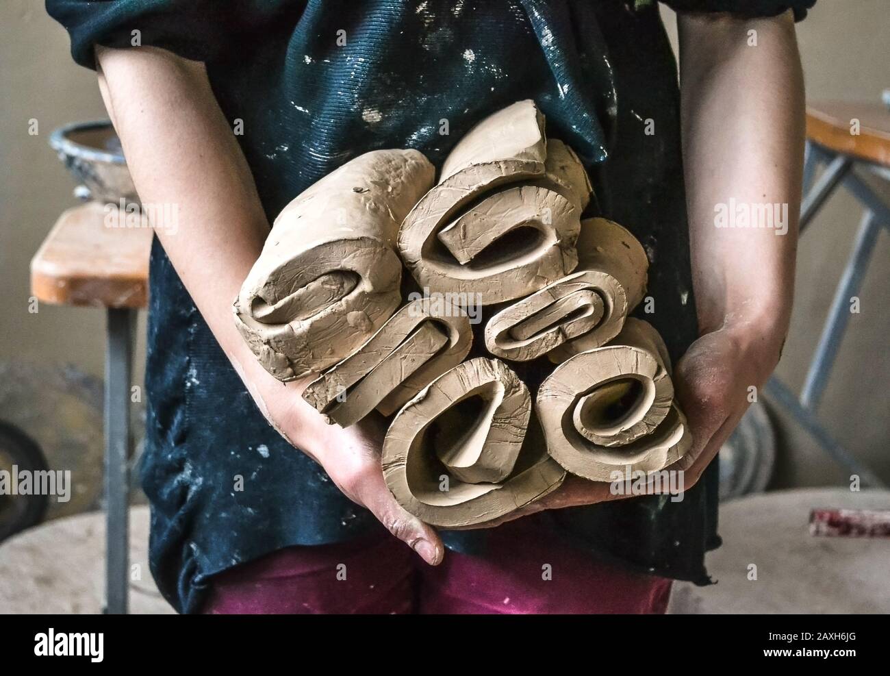 Master potter girl holding a many cut and twisted layers roll of clay ...