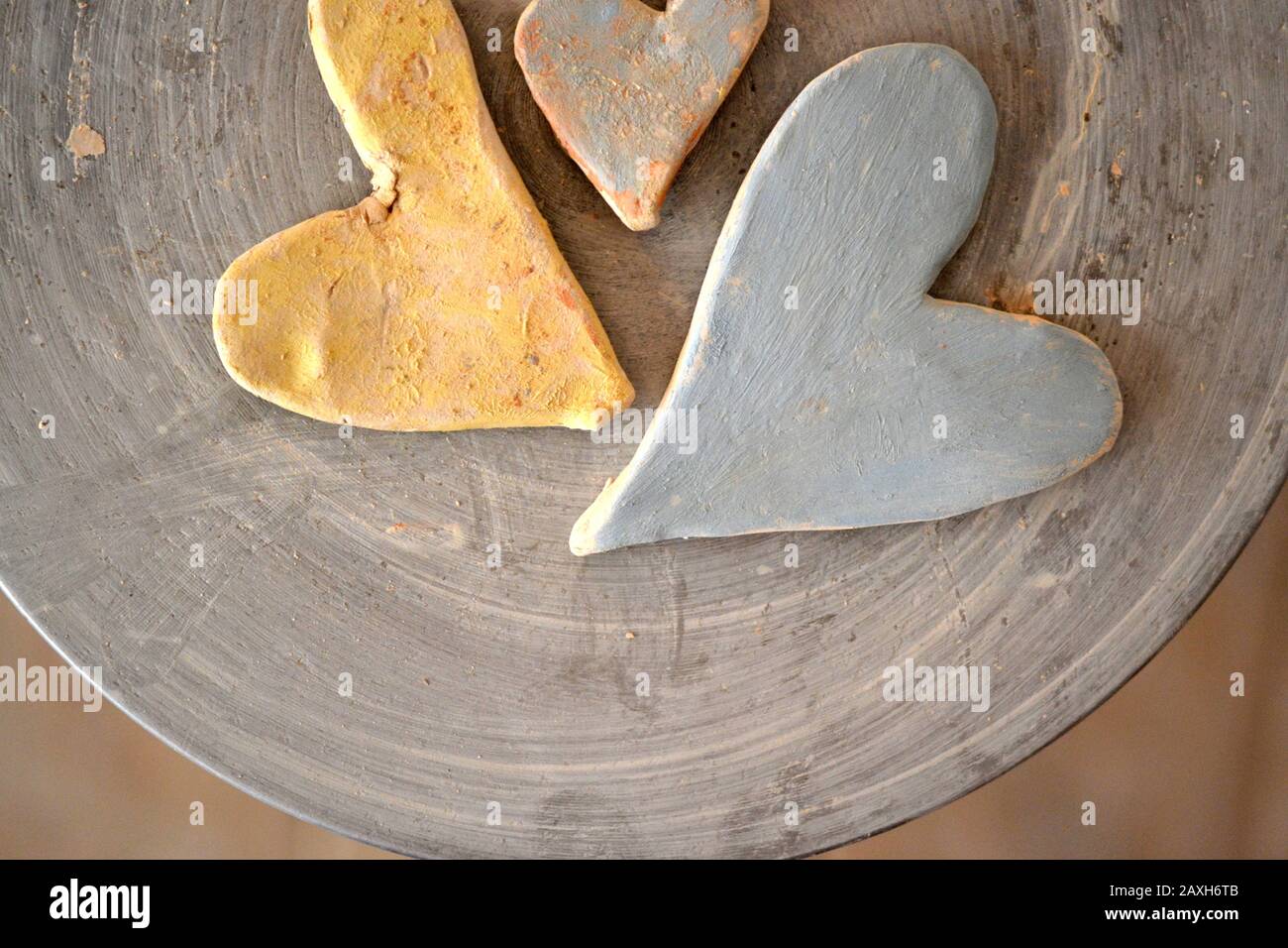 Three clay hearts painted with paints on a potter's wheel top view ...