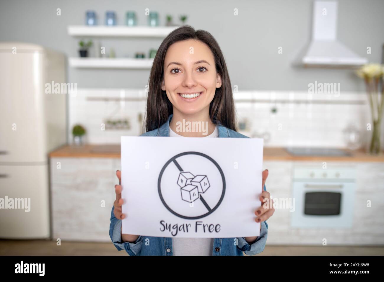 Smiling young woman holding no sugar sign Stock Photo - Alamy