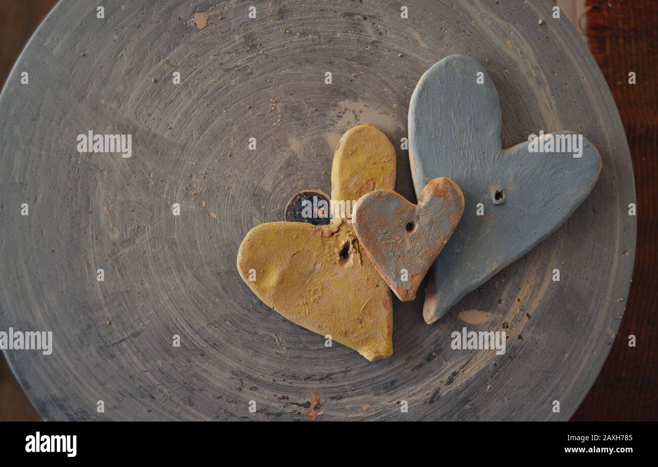 Three clay hearts painted with paints on a potter's wheel top view ...