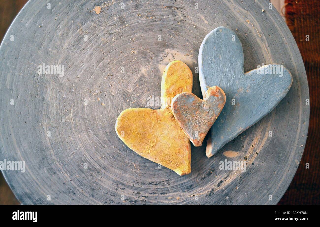 Three clay hearts painted with paints on a potter's wheel top view ...