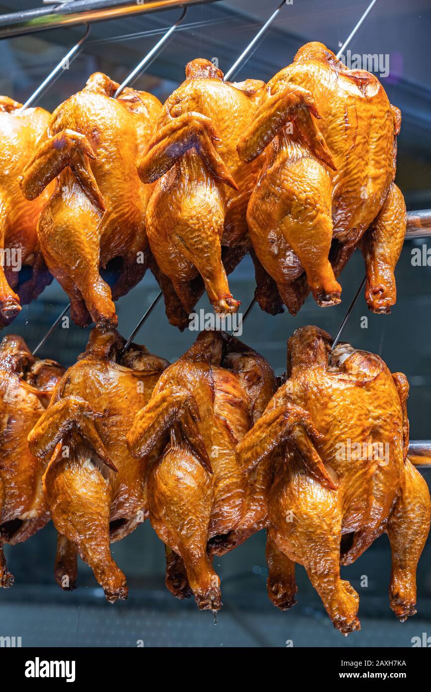 Closeup photo of whole roasted chicken hang at restaurant's showcase ...