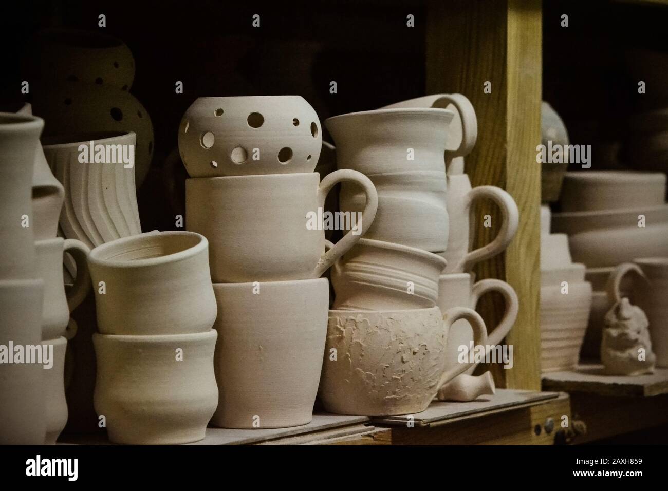 Bright pottery. Many white, not painted clay pottery standing on wooden ...