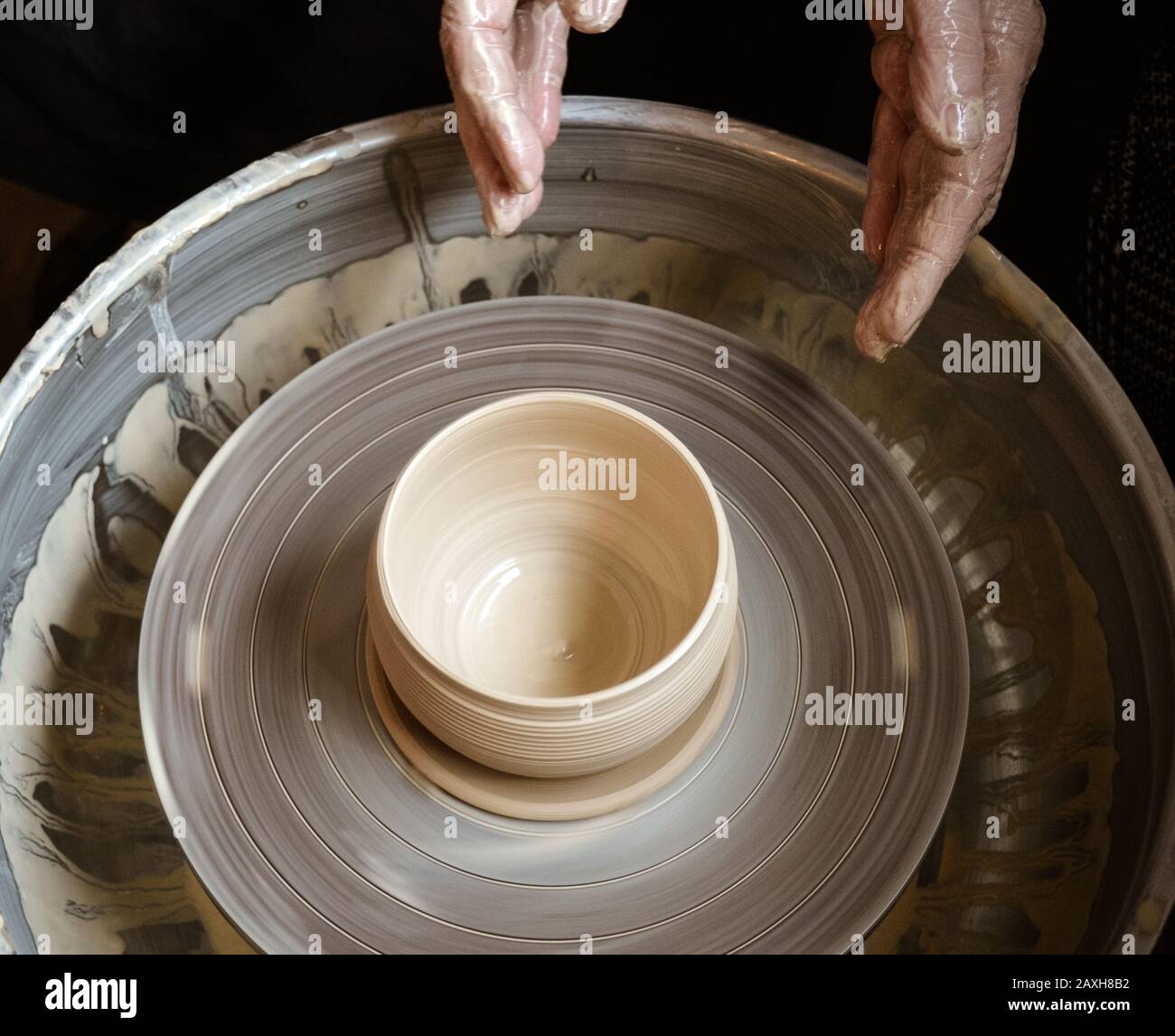 Hands of the master potter and vase of clay on the potter's wheel close ...