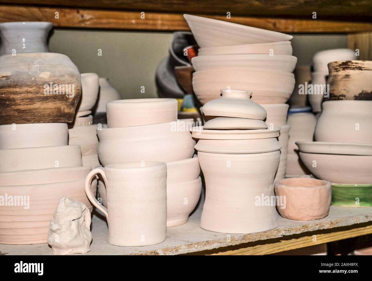 Bright pottery. Many white, not painted clay pottery standing on wooden ...