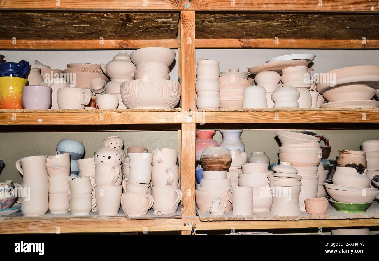 Bright pottery. Many white, not painted clay pottery standing on wooden ...